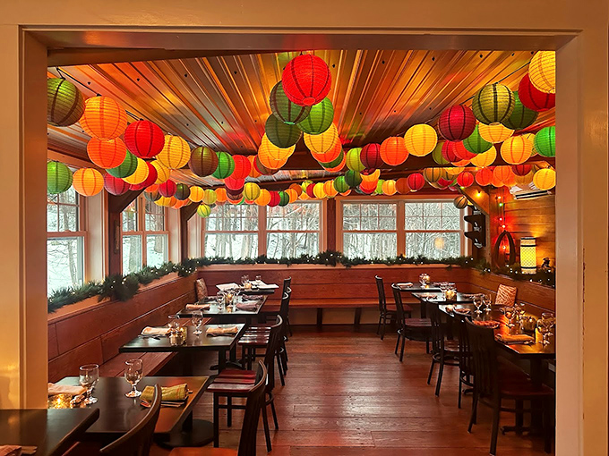 Paper lanterns dance across the ceiling in a festive display, while winter woods create a magical backdrop through wall-to-wall windows.