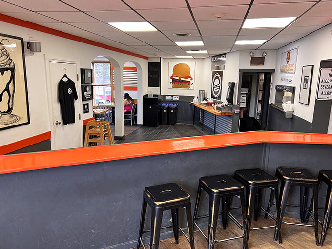 Modern meets nostalgic in this bright interior, where black metal stools and orange accents create a space that's both trendy and timeless.