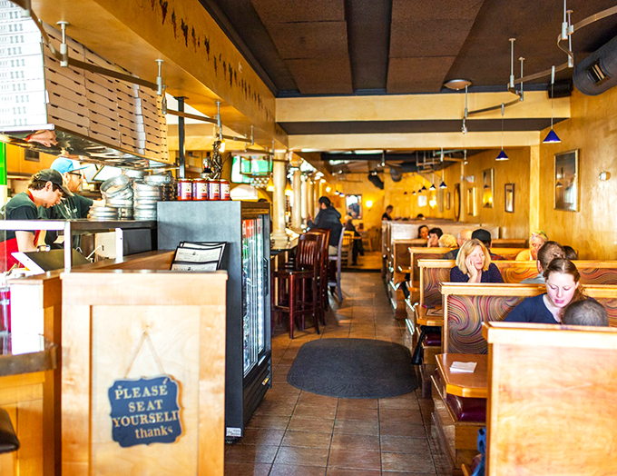 Please seat yourself, says the sign. It's like they're inviting you to make yourself at home in this cozy, golden-hued pizza sanctuary.