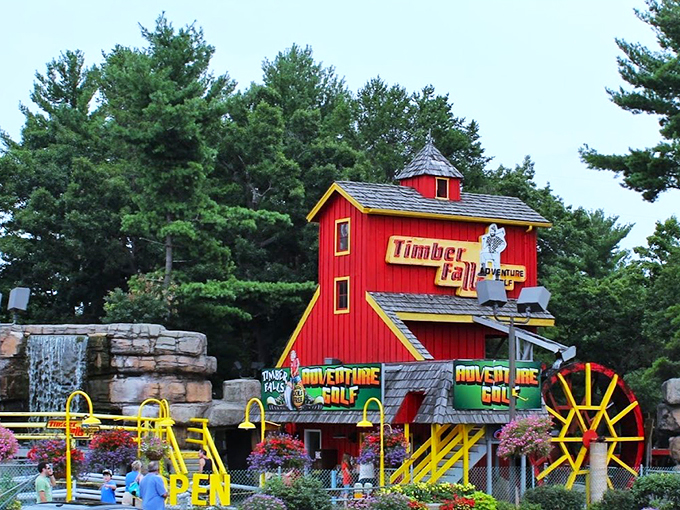 The charming red barn facade and cascading waterfall create a rustic playful wonderland that's pure Northwoods nostalgia.