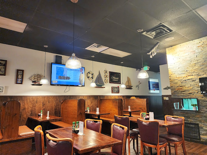 Wooden booths, warm lighting, and model ships sailing the walls—it's like stepping into a charming coastal tavern.