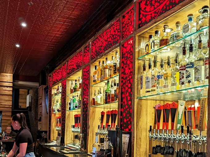 A craft cocktail lover's dream: Illuminated bottles gleam against red wallpaper while beer taps stand ready for thirsty patrons.