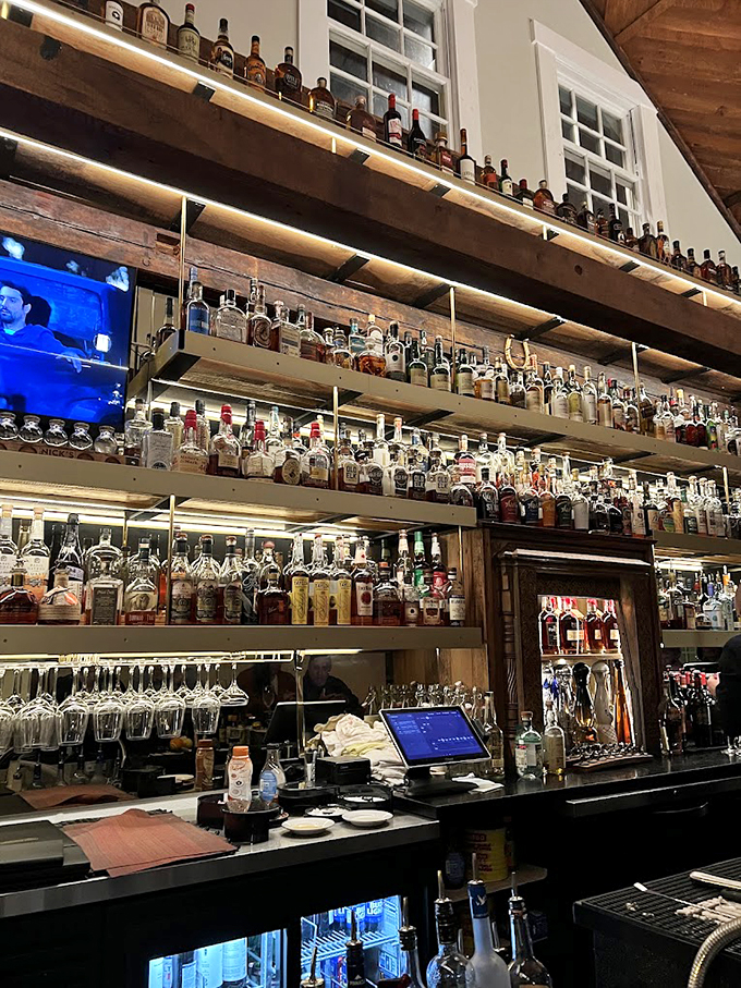 The bar's impressive collection of spirits stretches skyward, a liquid library that would make any cocktail enthusiast weak in the knees. Photo credit: Chris Wisneski