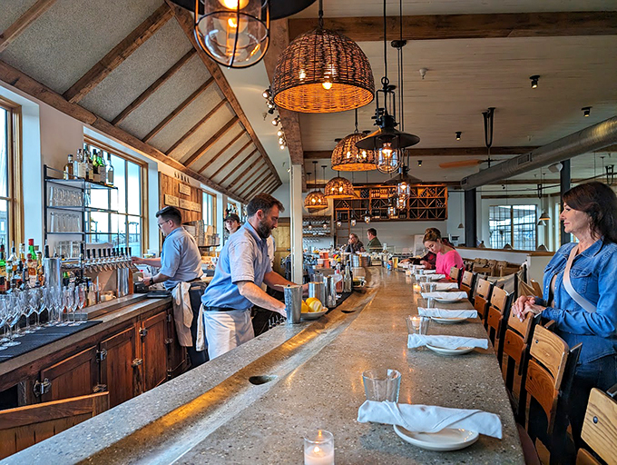 The bar's woven basket lights cast a golden glow, while mixologists craft cocktails beneath an impressive wine collection. Photo credit: Thomas Thompson, MD, PhD