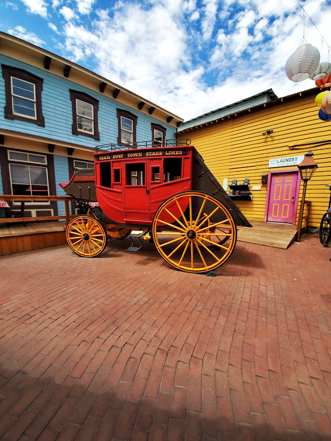 A beautifully restored stagecoach stands ready for its close-up, flanked by charming Old West buildings in cheerful desert hues.