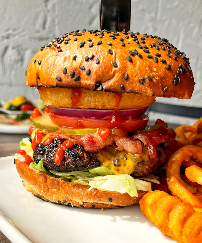 This towering masterpiece of beef and toppings on a black sesame bun isn't just a burger - it's edible architecture.