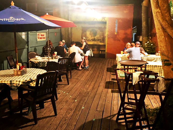 String lights twinkle above the wooden deck, where checkered tablecloths and summer breezes make every meal feel like a backyard party.