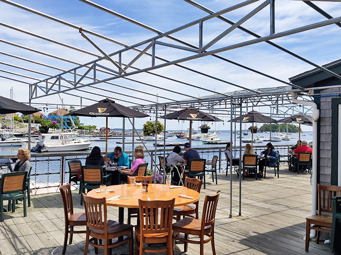 The deck offers front-row seats to Camden's harbor ballet, where boats dance and Guinness umbrellas provide shade for seafood stories. Photo credit: RĆ