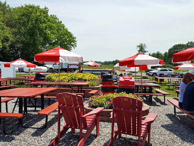 Red Adirondack chairs and umbrella-shaded picnic tables create the perfect summer seafood scene, complete with blooming flower gardens.