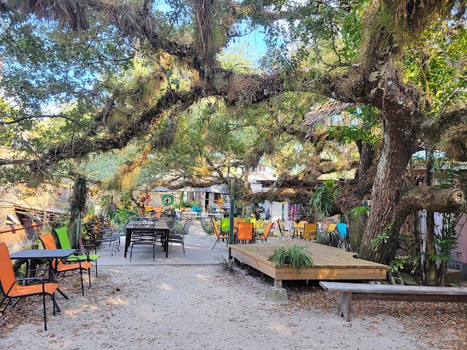 Spanish moss drapes over colorful chairs, creating nature's own dining room where Old Florida meets artistic eccentricity.