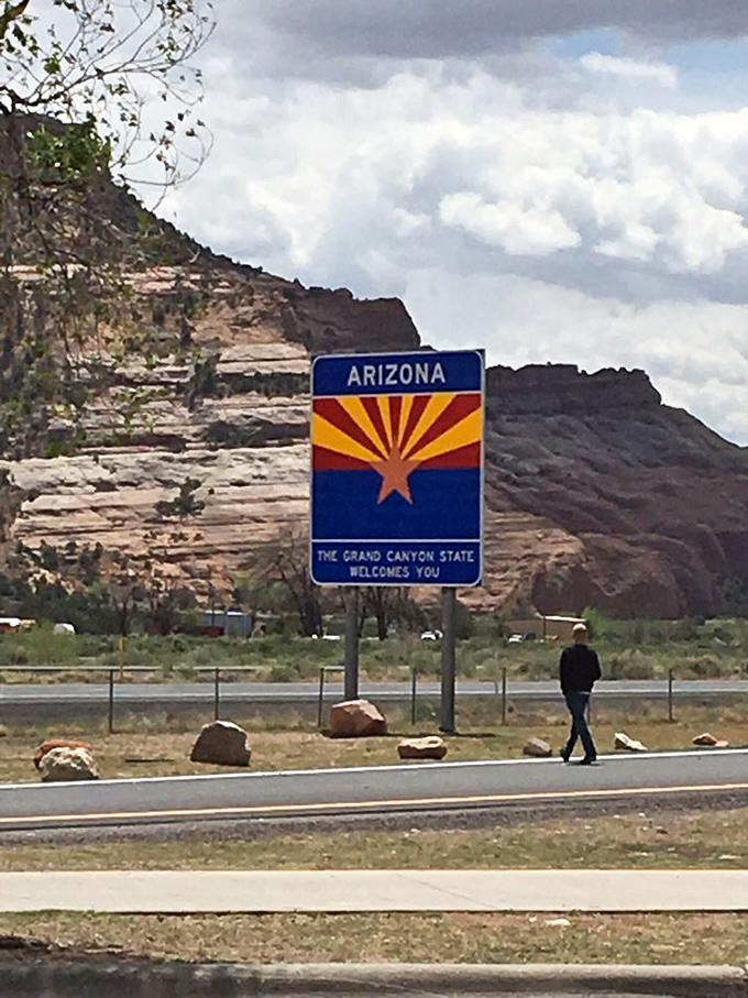 Even the rocks are excited you're here! This sign stands tall against a backdrop that's been millions of years in the making. Photo credit: Denise S.