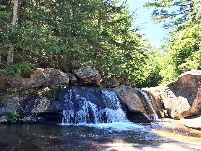 The water splits around this stubborn boulder like a liquid curtain, creating nature's own theatrical performance.