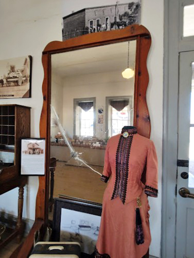 A perfectly preserved period dress stands sentinel beside an antique mirror, offering glimpses into Florence's fashionable frontier days.