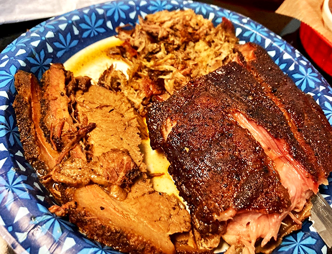 Behold the holy trinity of BBQ! This plate of brisket, pulled pork, and ribs is a carnivore's dream come true.