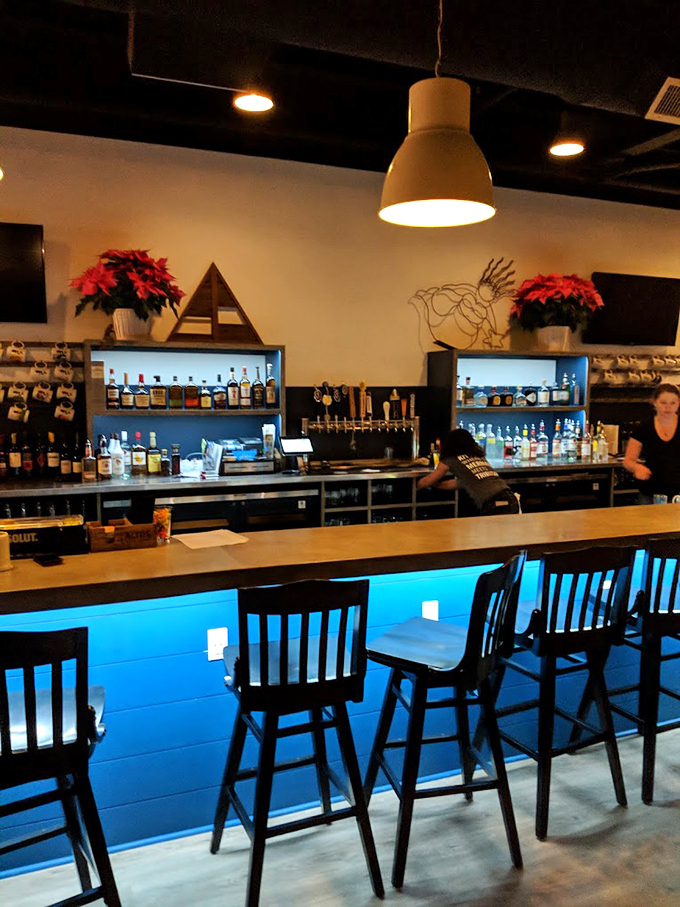 The bar glows with ocean-blue lighting beneath, while poinsettias add festive touches above &ndash; tropical meets New England charm. Photo credit: Eddie Webbinaro