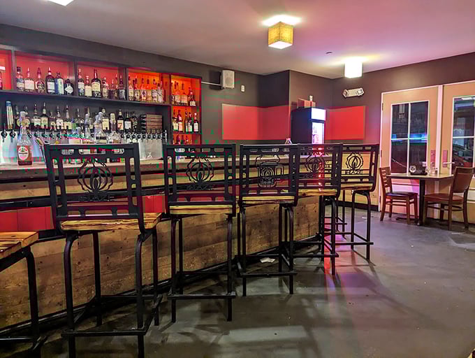 Custom metalwork bar stools line the rustic wooden counter, where craft cocktails and local brews flow freely beneath amber pendant lights. Photo credit: Anuj Sharma