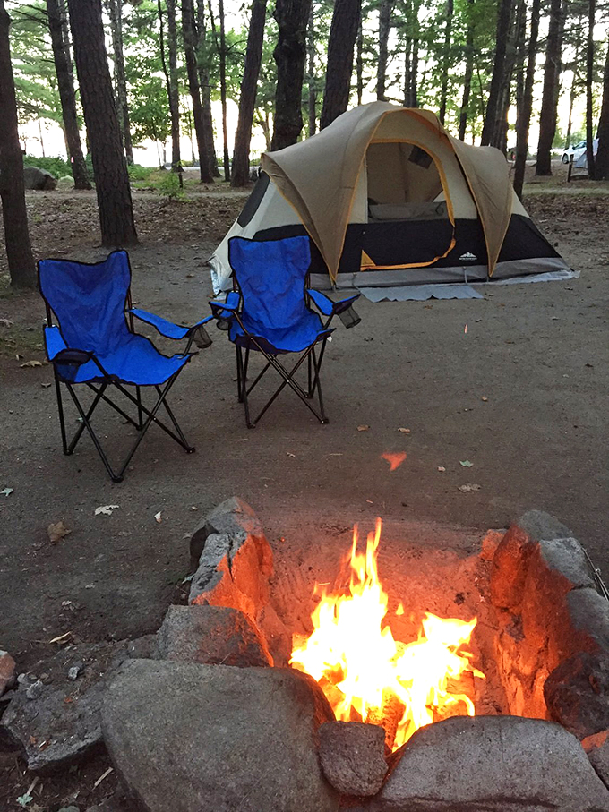 Camping goals: A cozy tent, crackling campfire, and comfy chairs create the perfect outdoor living room under Maine's towering pines. 