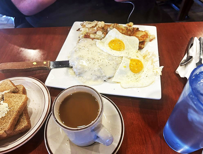 Two sunny-side-up eggs crown this hearty breakfast plate, ready to share their golden goodness with crispy hashbrowns.