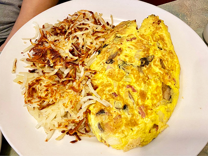 A perfectly executed omelet shares the plate with hash browns so crispy they deserve their own fan club.