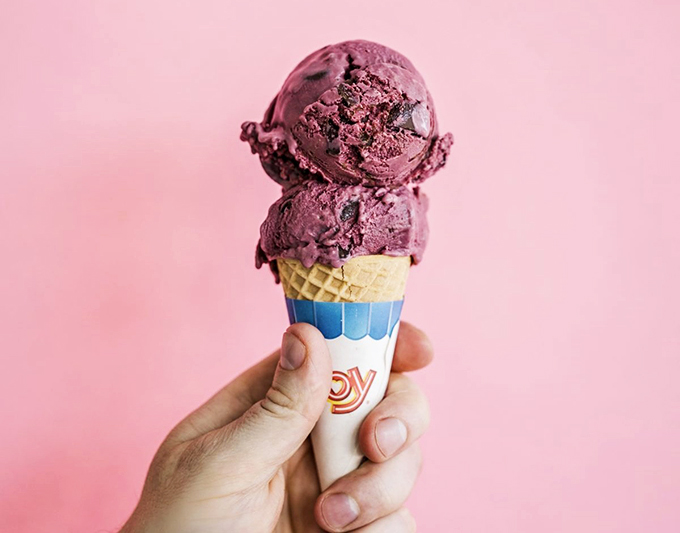 Two perfectly stacked scoops of rich chocolate ice cream perch atop a classic waffle cone, like a delicious tower of happiness.