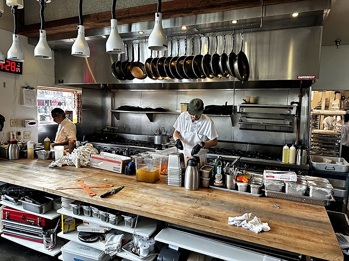Behind the scenes, a pristine kitchen line stands ready for service, with well-worn cast iron pans hanging like medals of honor. Photo credit: Peter Papp