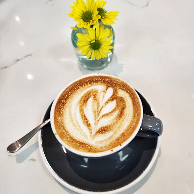 Art meets caffeine in this perfectly poured matcha latte, sitting pretty next to cheerful yellow daisies. 