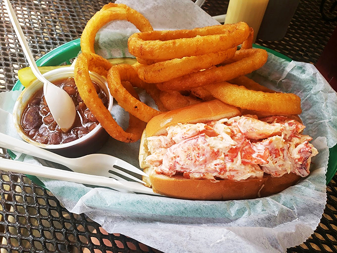 This lobster roll isn't just a sandwich - it's a celebration of Maine's coastal heritage, served with golden onion rings.