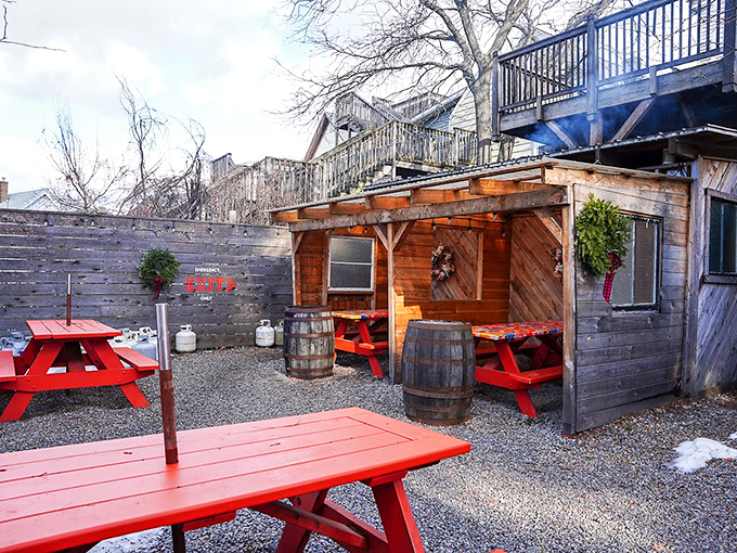 Red picnic tables and rustic barrels transform this outdoor space into a cozy BBQ hideaway, complete with Maine winter-defying charm. Photo credit: Benjamin Moore