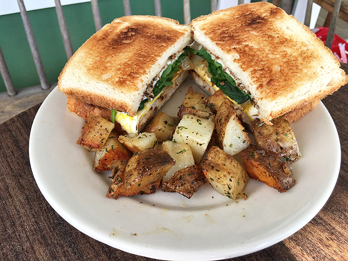 Golden-brown toast hugs fresh ingredients while seasoned home fries stand guard &ndash; breakfast perfection on a plate. 