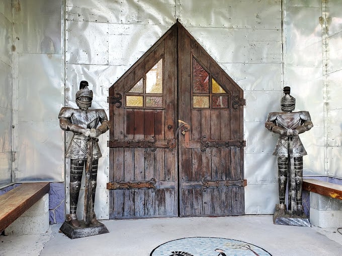 Medieval meets metallic as two stoic knights guard this rustic wooden entrance, looking like they're ready for a very shiny crusade.