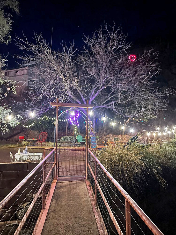 String lights twinkle above a whimsical bridge, while a heart-shaped neon sign reminds us that magic still exists.