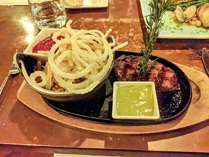 This isn't just beef tenderloin &ndash; it's a masterpiece served with crispy onion rings and a sauce that demands bread-soaking. Photo credit: Curt Raffi