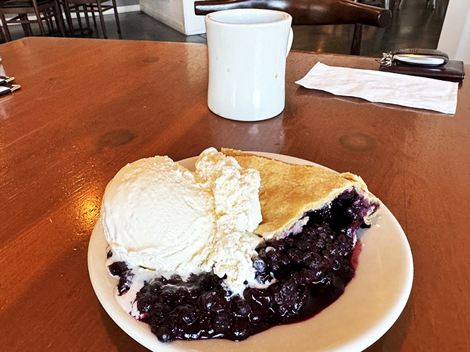 A slice of wild blueberry pie meets its soulmate: a generous scoop of vanilla ice cream melting into berry perfection.