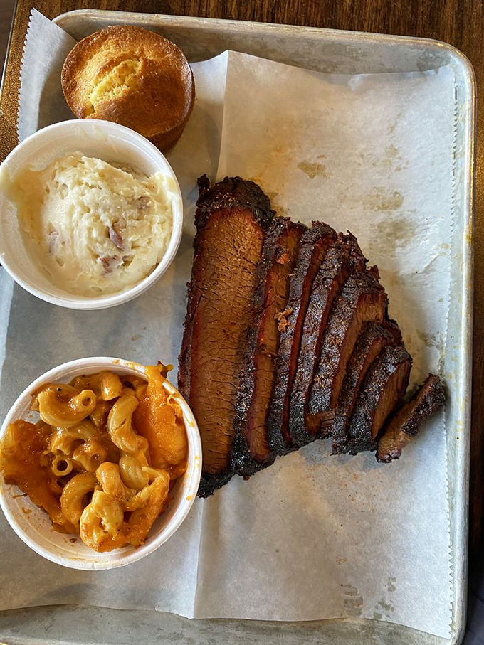 Behold the brisket in all its glory, sporting that perfect smoke ring like a badge of honor alongside those famous mashed potatoes.