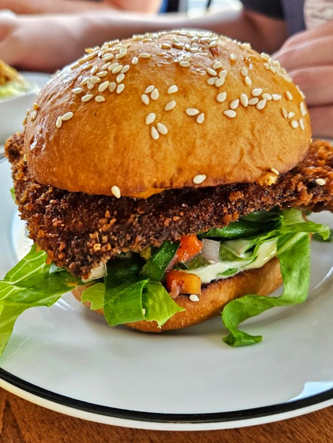 A sesame-studded bun crowns this beauty like a royal crown, with fresh lettuce adding a crisp green flourish.