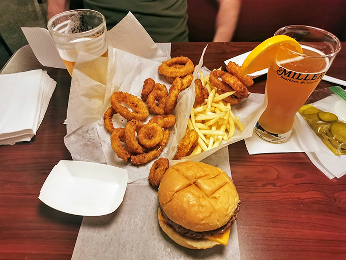 The holy trinity of comfort food: a juicy burger, golden onion rings, and crispy fries, all washed down with a cold one.