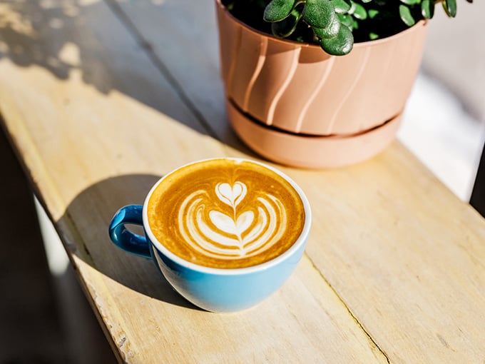 A perfectly poured latte shows off its heart-shaped art, proving that sometimes love comes in a blue ceramic cup.