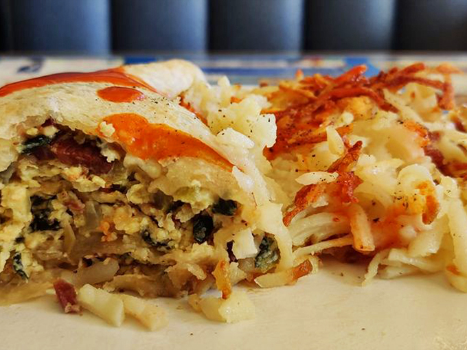 A masterpiece of morning engineering: eggs, veggies, and cheese wrapped in a perfect tortilla package, with crispy hash browns standing guard.