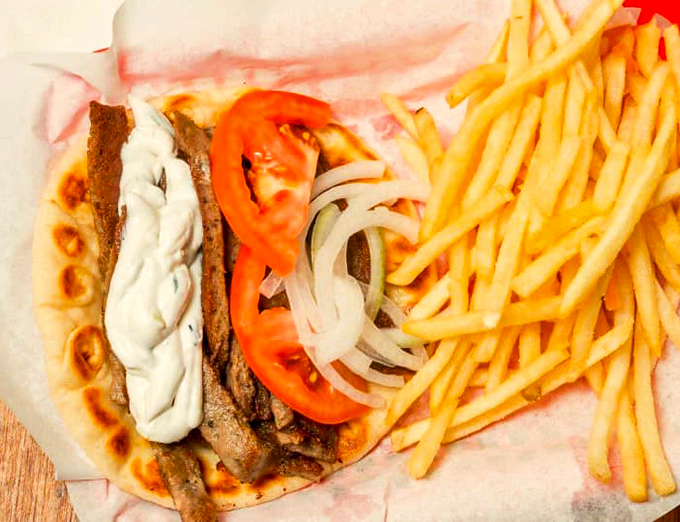 Fresh-sliced gyro meat, crisp vegetables, and creamy tzatziki create a handheld feast that demands both hands and napkins.