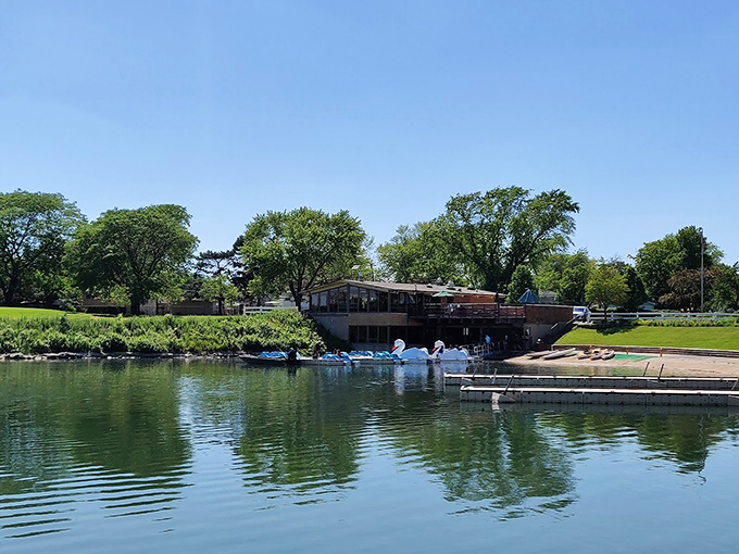 The lake's mirror-like surface reflects clouds and trees, creating a double dose of natural beauty in Des Plaines' urban oasis