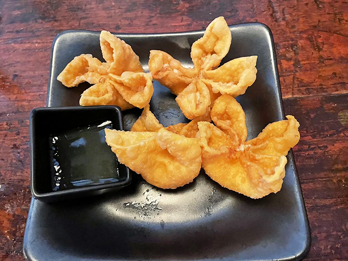 Golden-fried rangoons bloom like delicate flowers, hiding a treasure of cream cheese and lobster within.