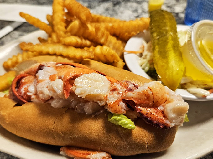 This isn't just a lobster roll - it's a celebration of Maine's finest, served with golden fries and a pickle standing guard. Photo credit: Holly A