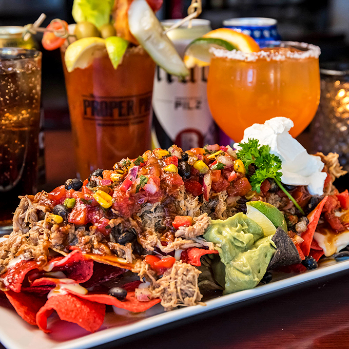 A mountain of pulled pork nachos that could feed a small army, crowned with fresh veggies and drizzled with pure joy.