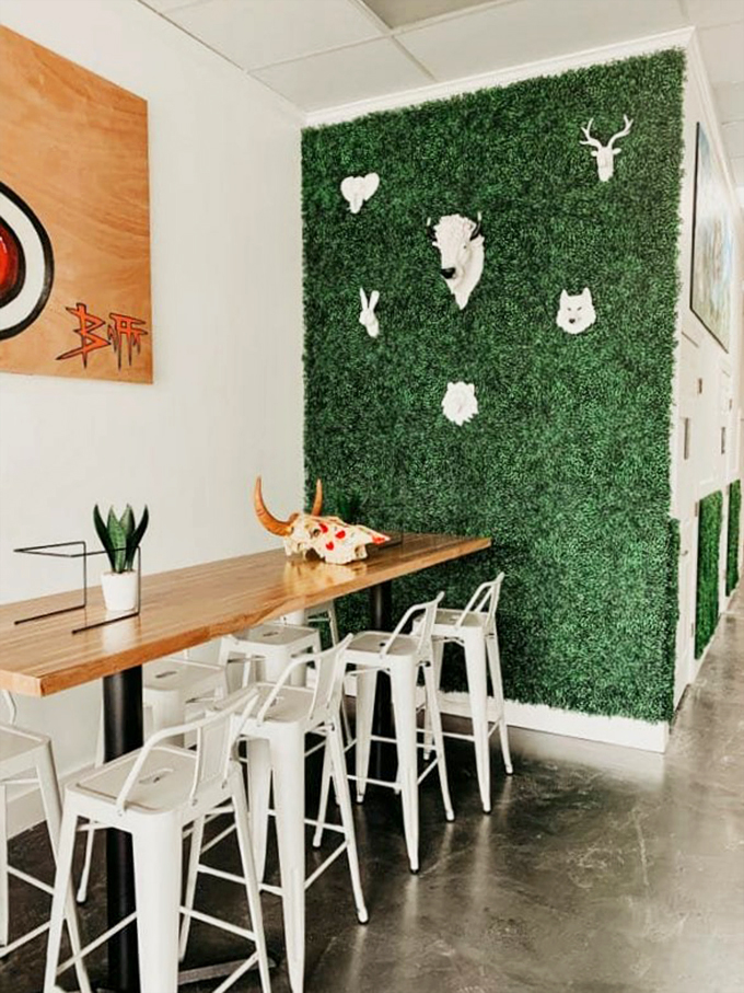 A creative corner where white animal silhouettes pop against emerald artificial turf, creating an Instagram-worthy dining spot that's uniquely Naples.