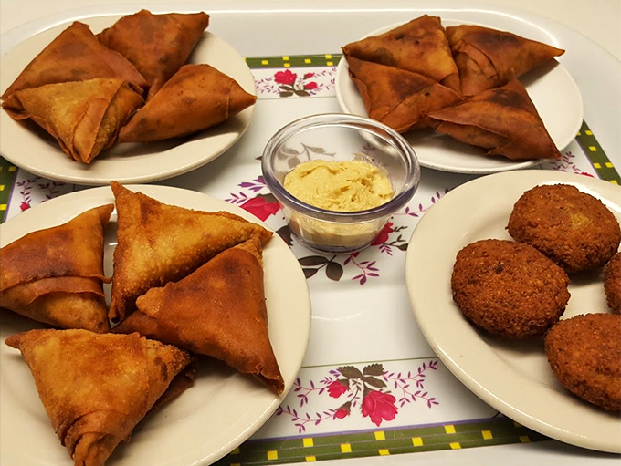 The ultimate African appetizer spread: crispy sambusas and perfectly spherical falafel that could make a food photographer weep with joy.