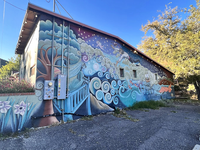 A dreamy mural flows across the wall like a visual poem, bringing whimsy and wonder to this historic corner. 