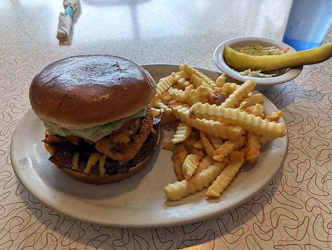 Holy cow, that's a burger! This beefy behemoth is flanked by golden crinkle-cut fries and a pickle spear. It's not just a meal, it's a delicious challenge waiting to be conquered.