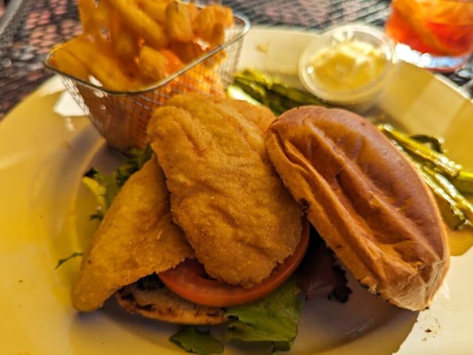 The legendary perch sandwich arrives like a golden-crusted crown jewel, with crispy fries standing at attention in their metal basket throne.