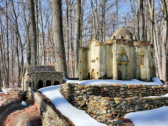 Winter transforms this handcrafted grotto into a snow-dusted wonderland, where river rocks and concrete create an enchanting woodland sanctuary.