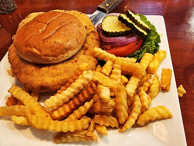 A golden-crusted sandwich meets crispy crinkle-cut fries, with fresh vegetables standing by for the perfect bite.